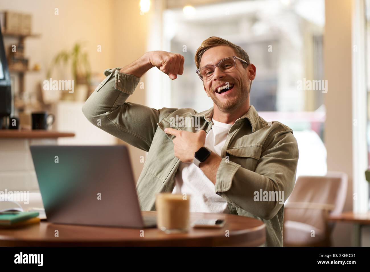 Portrait of handsome, pleased young man shows biceps, flexing muscles ...