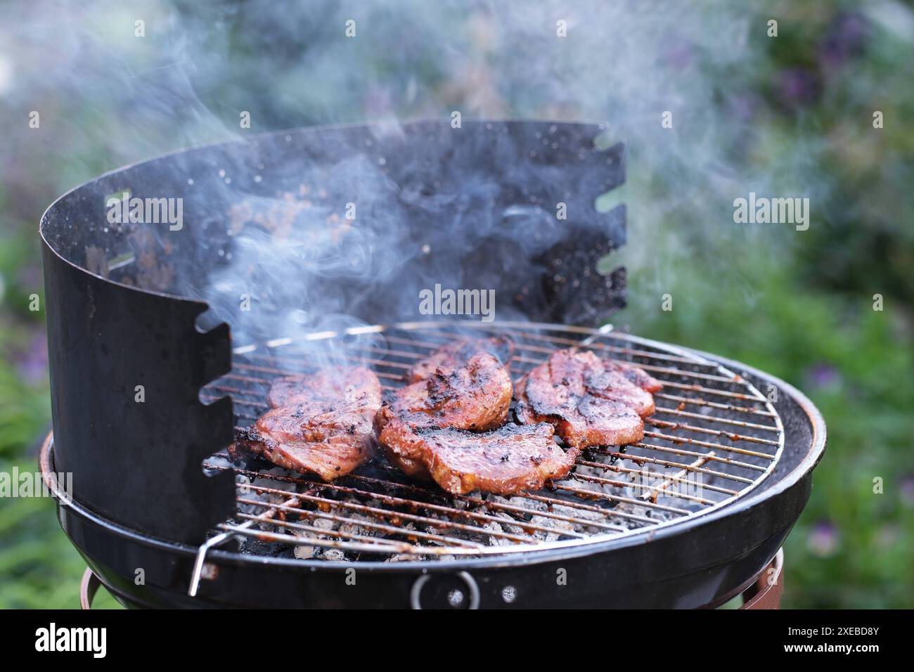 rauchender Holzkohlegrill in einem Garten. *** Smoking charcoal ...