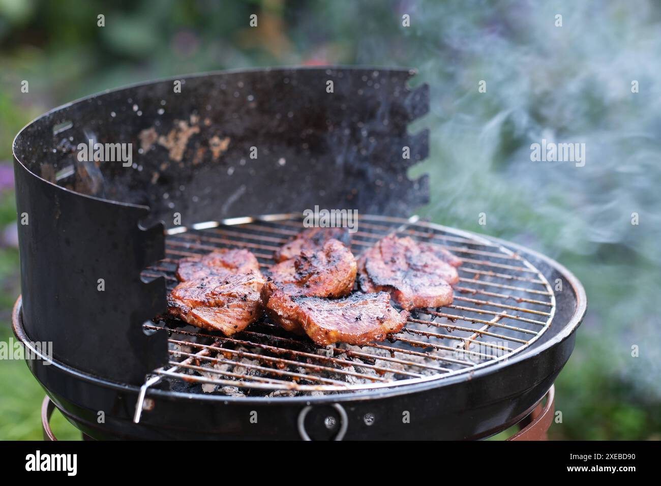 rauchender Holzkohlegrill in einem Garten. *** Smoking charcoal ...