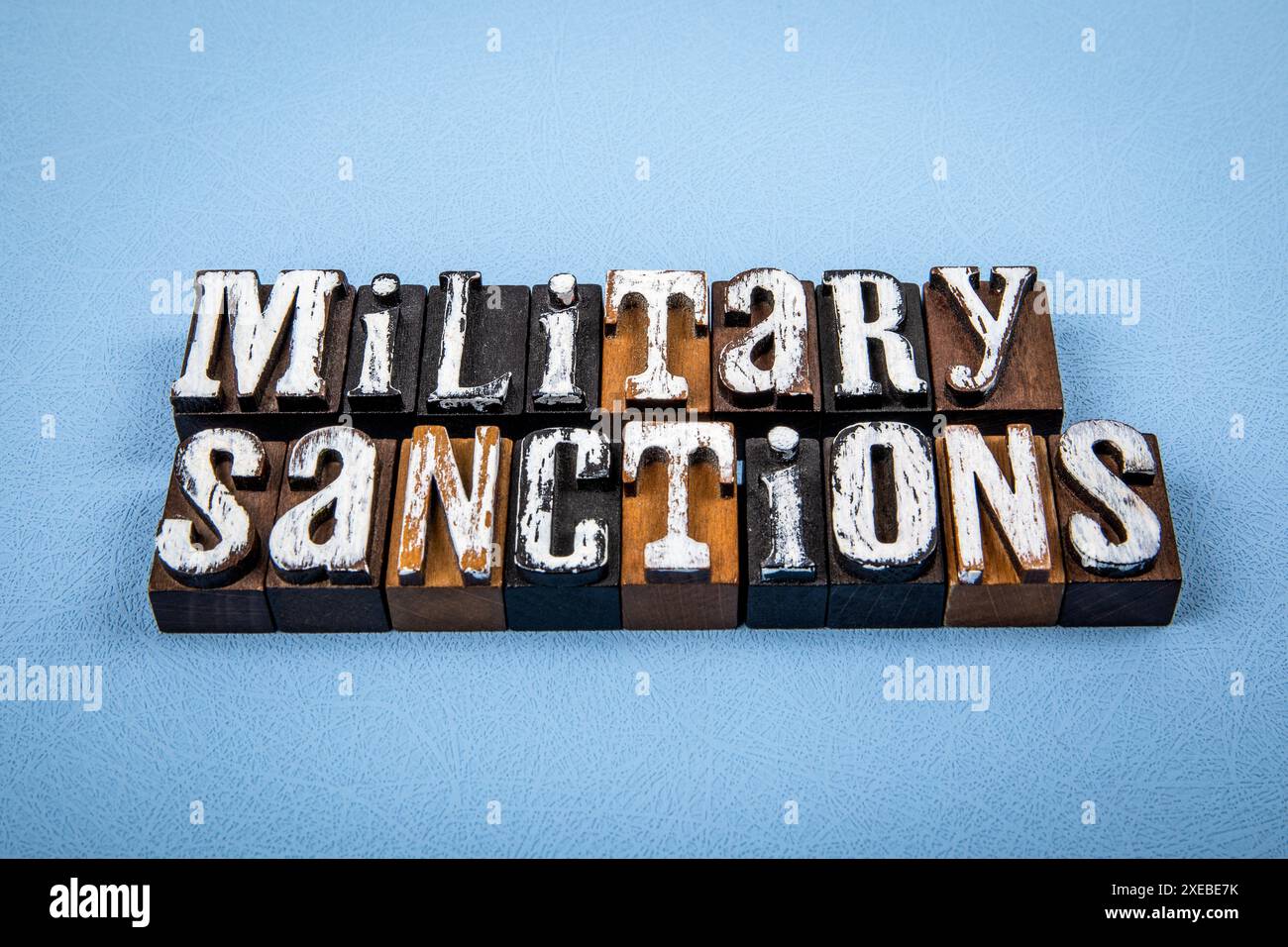 MILITARY SANCTIONS. Wooden alphabet letter blocks on blue textured ...