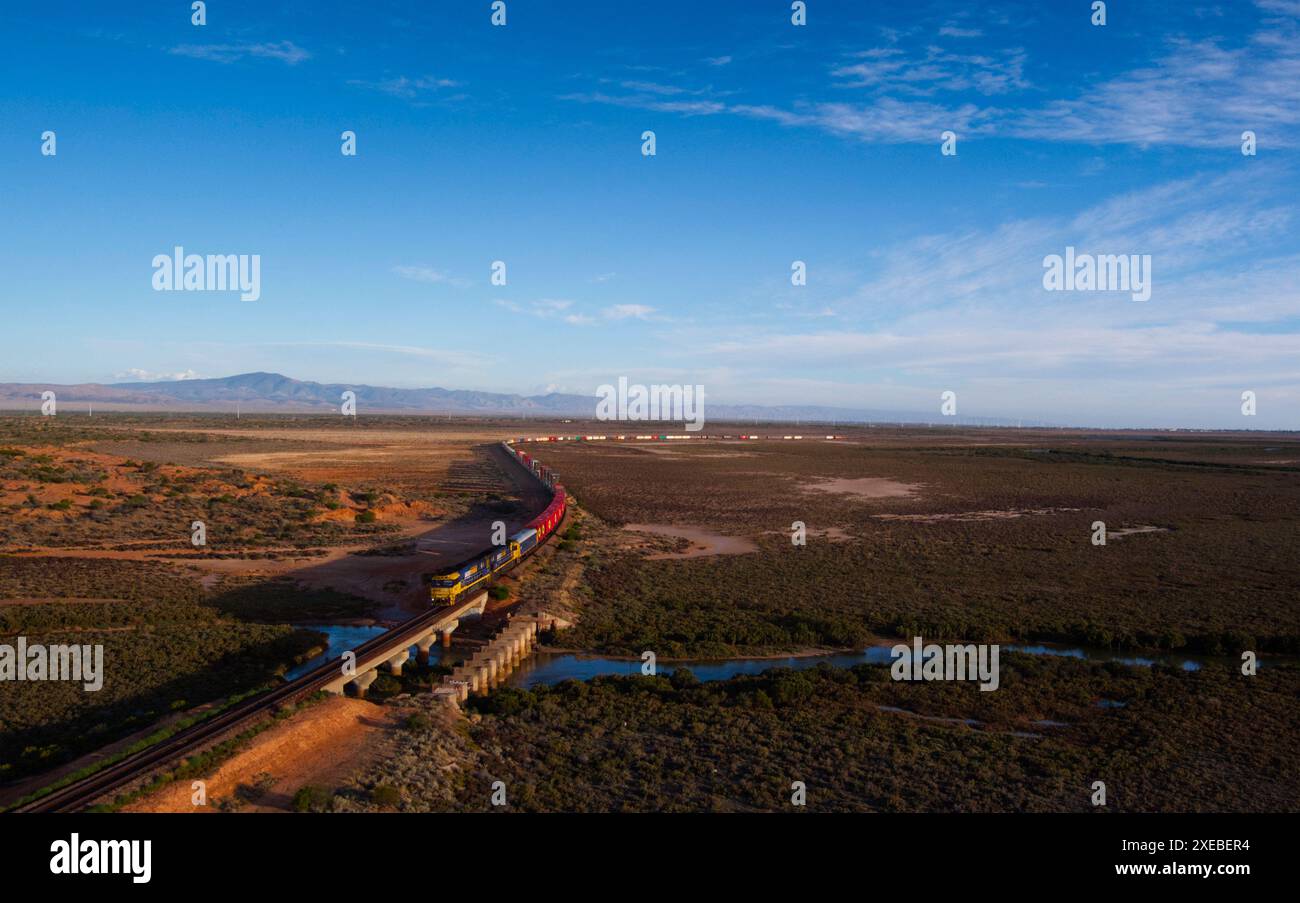 Aerial view of a freight train in motion, traveling through the outback ...