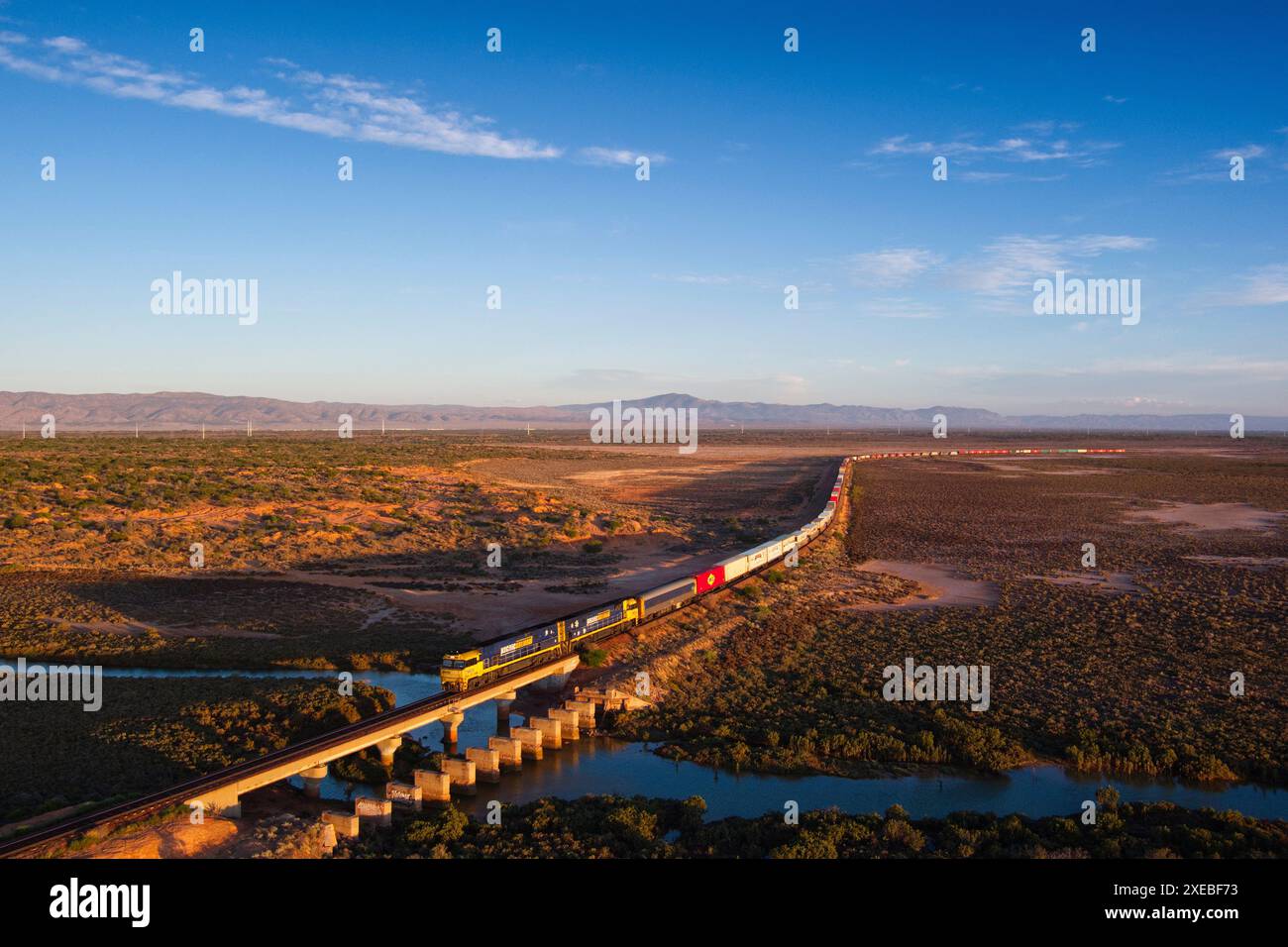 A intermodal freight container train crossing a bridge in the desert ...