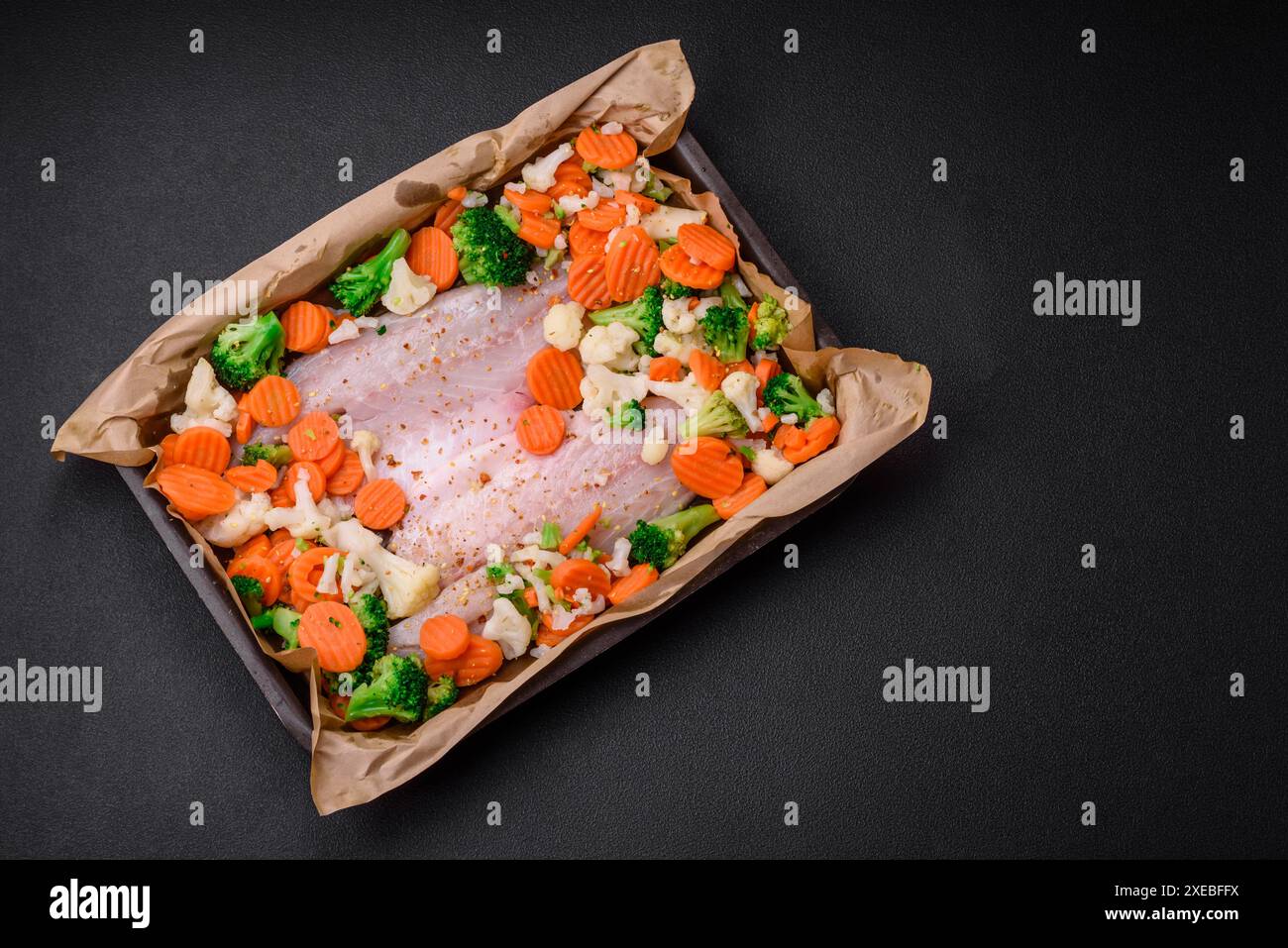 Raw sea bass fish fillet with salt, spices and vegetables in a baking ...