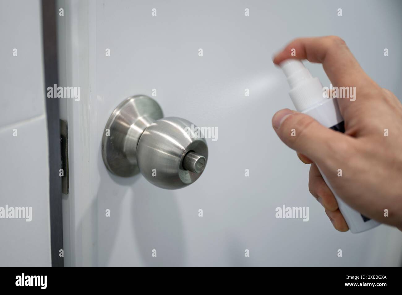 Finger pressing alcohol spray spraying to doorknob in toilet. Provent ...