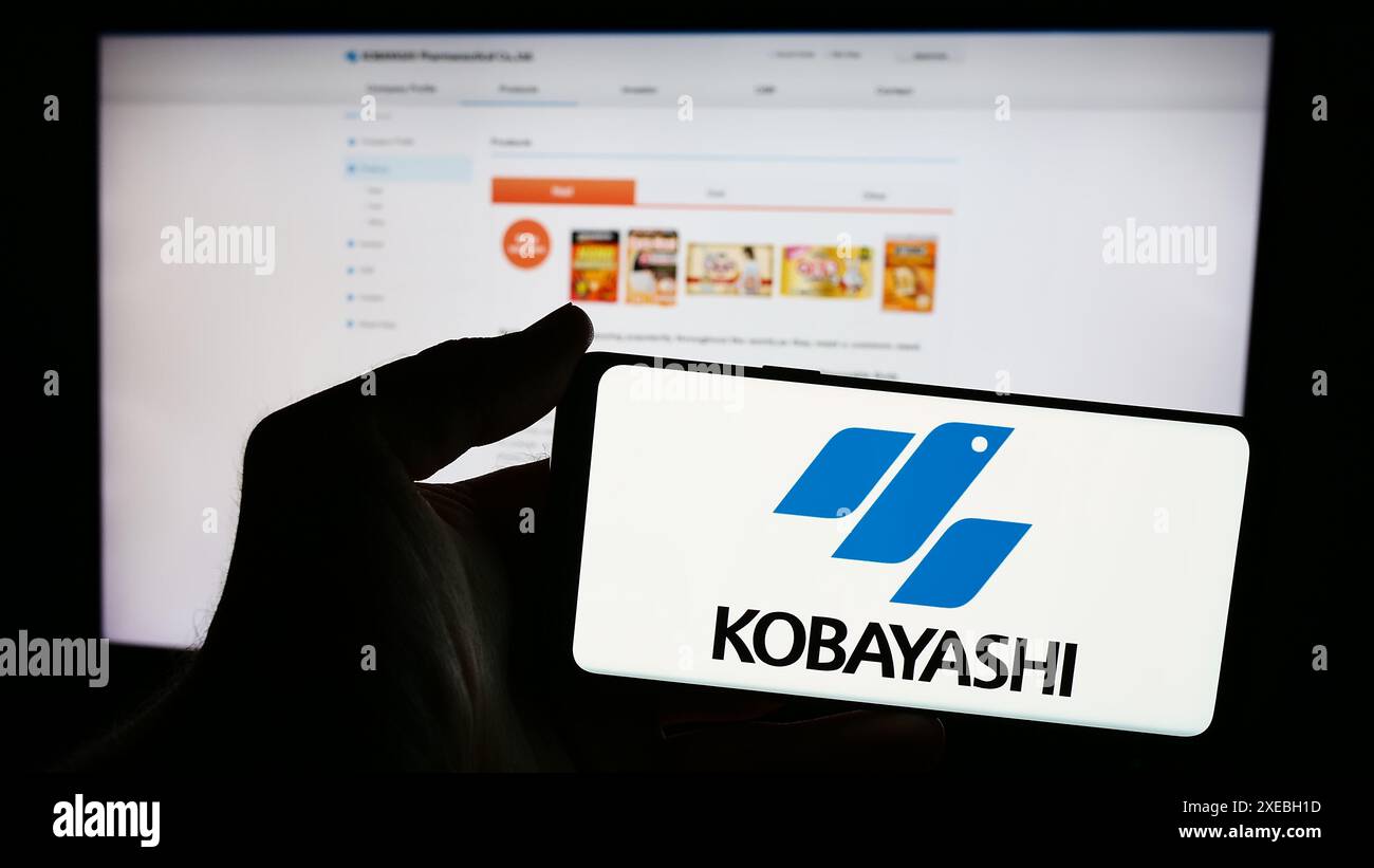 Person holding mobile phone with logo of Japanese company Kobayashi ...
