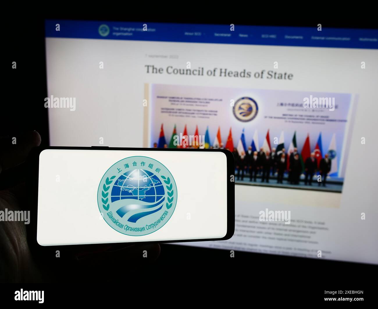 Person holding smartphone with logo of Eurasian Shanghai Cooperation ...