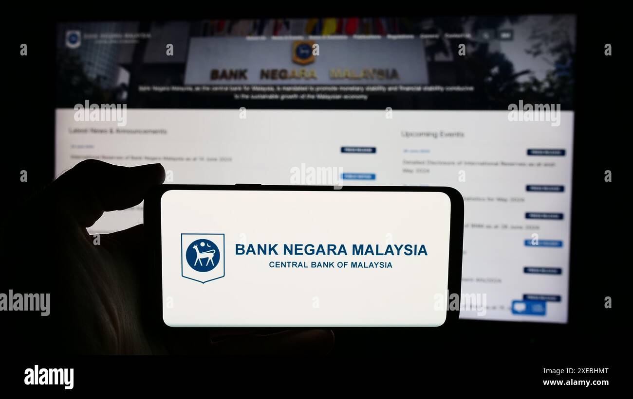 Person holding cellphone with logo of Malaysian institution Bank Negara ...
