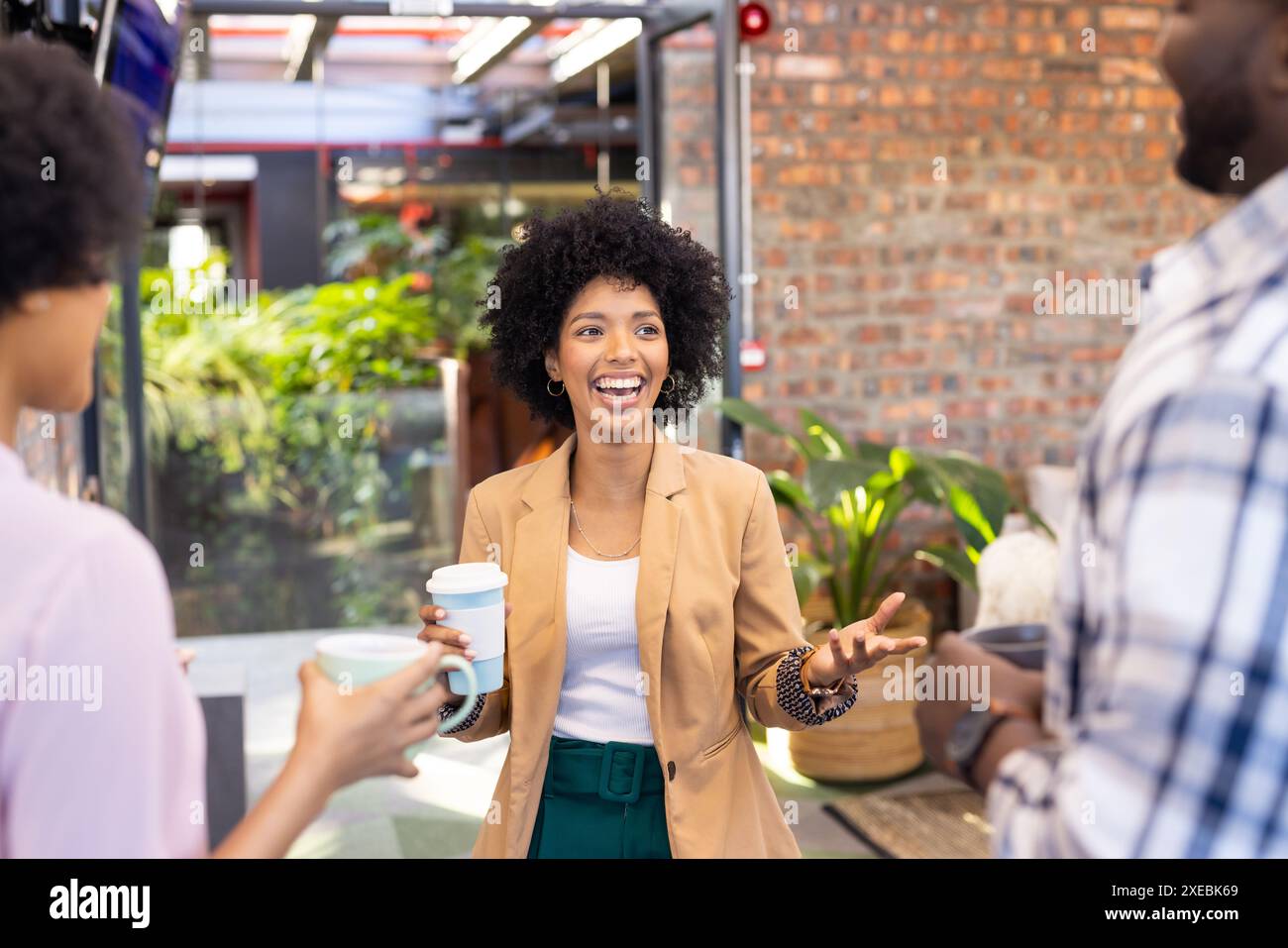 African American businesswoman holding coffee cup, talking with ...
