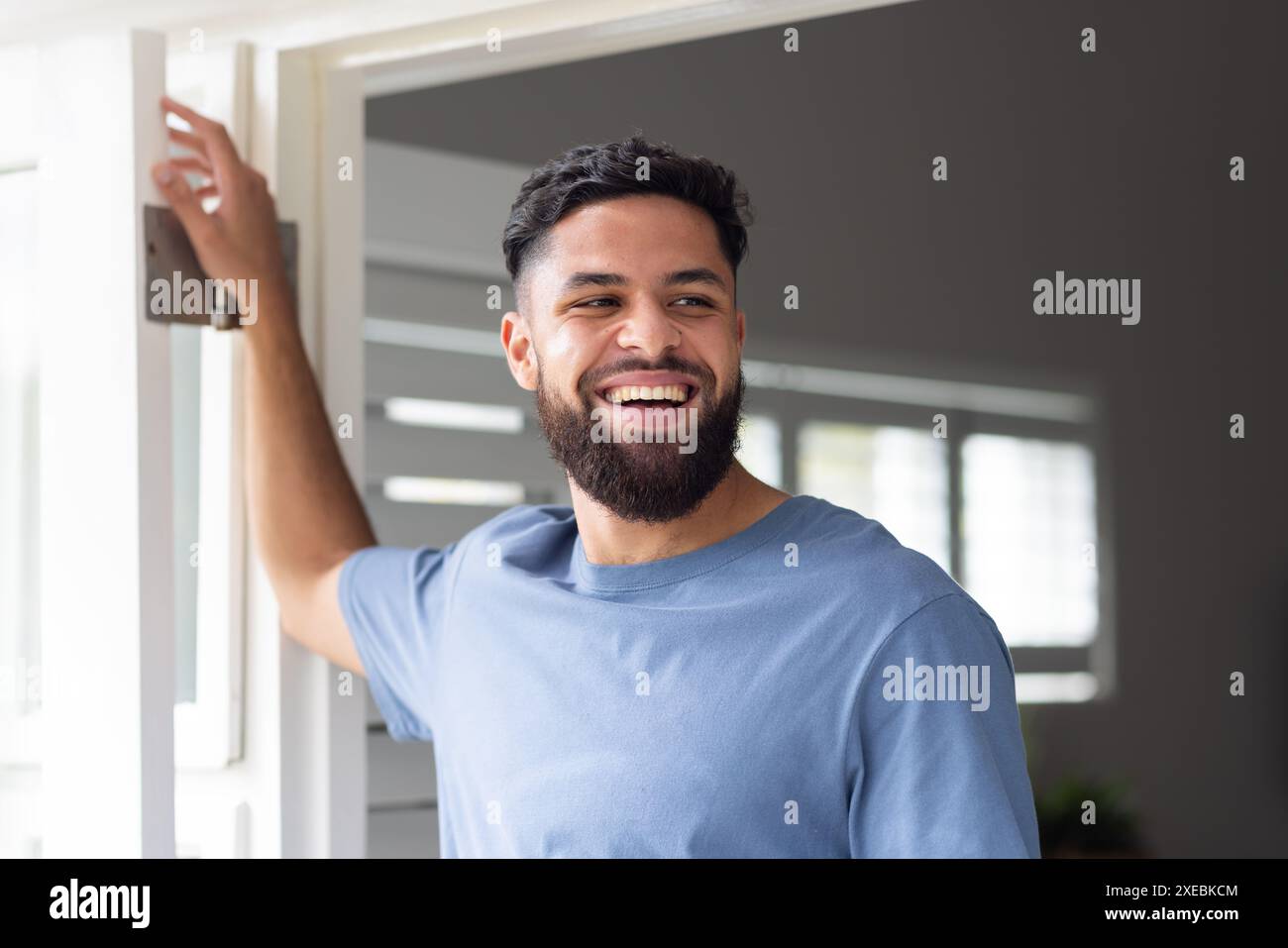 Smiling man standing at home, looking outside through open door Stock ...