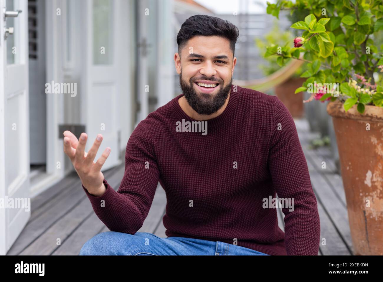 Smiling man sitting on porch, gesturing with hand, enjoying outdoor ...