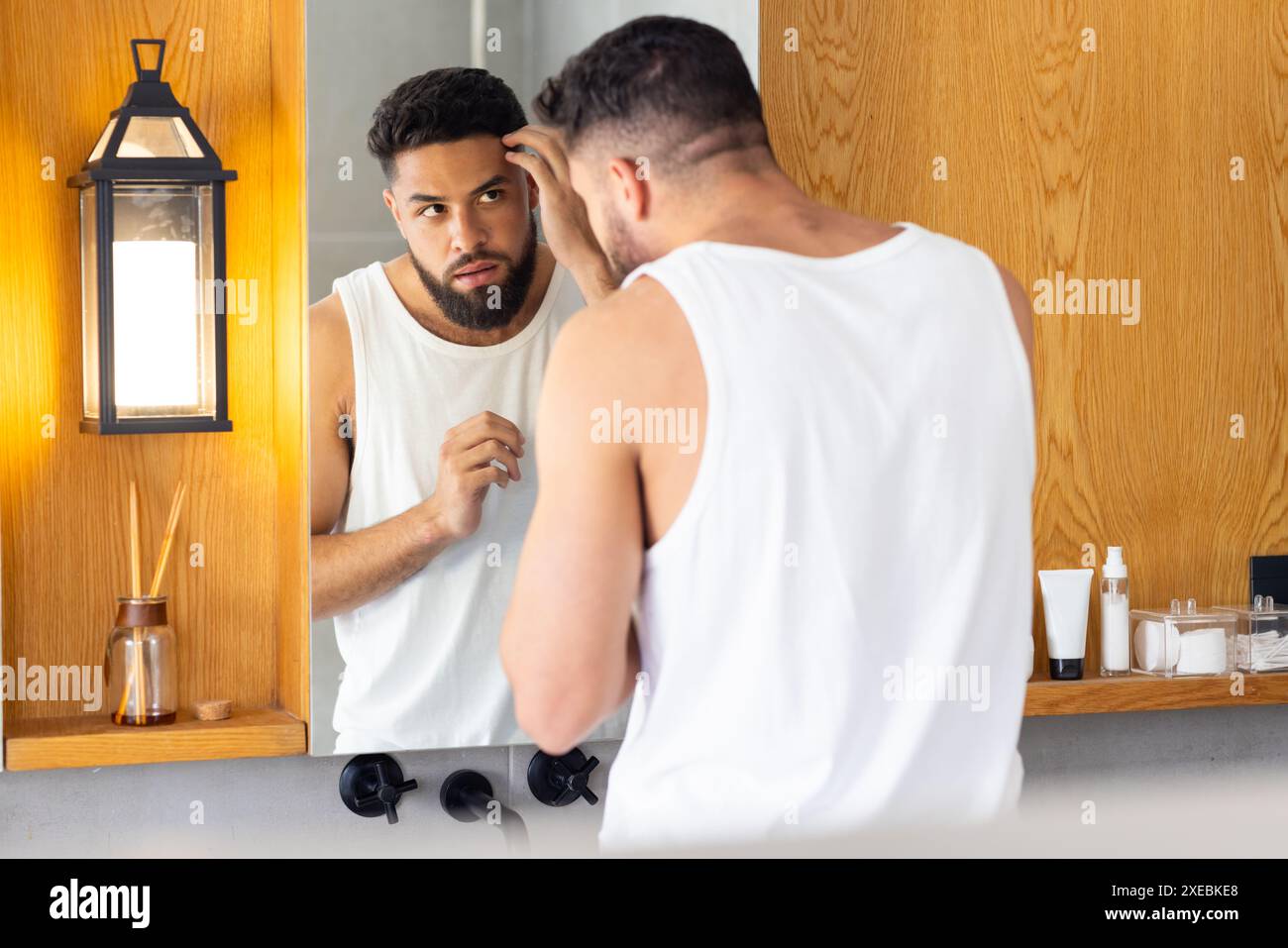 Grooming, man looking in mirror and styling hair in bathroom at home ...