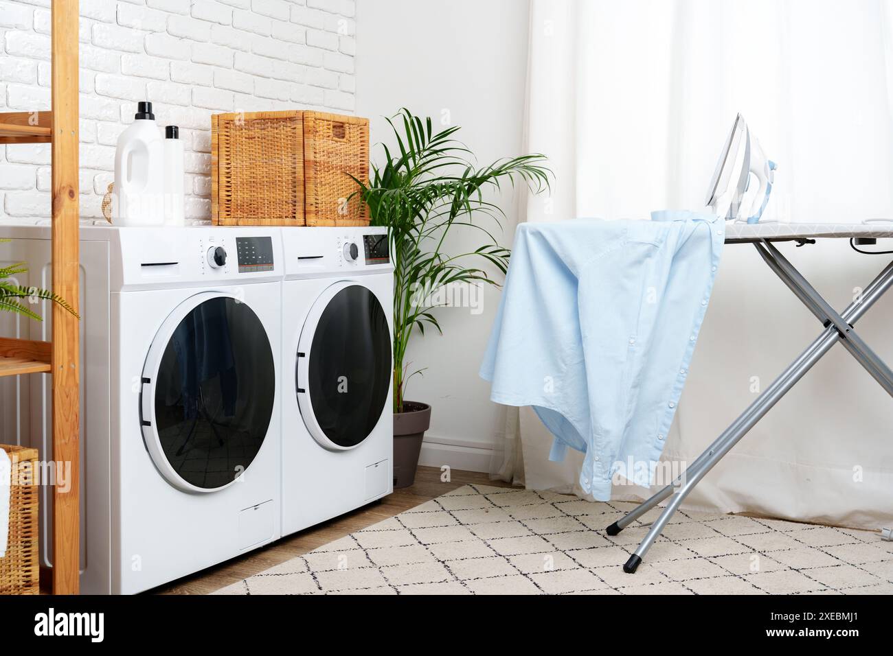 White Iron on Grey Ironing Board Next to Laundry Machines in White Room ...