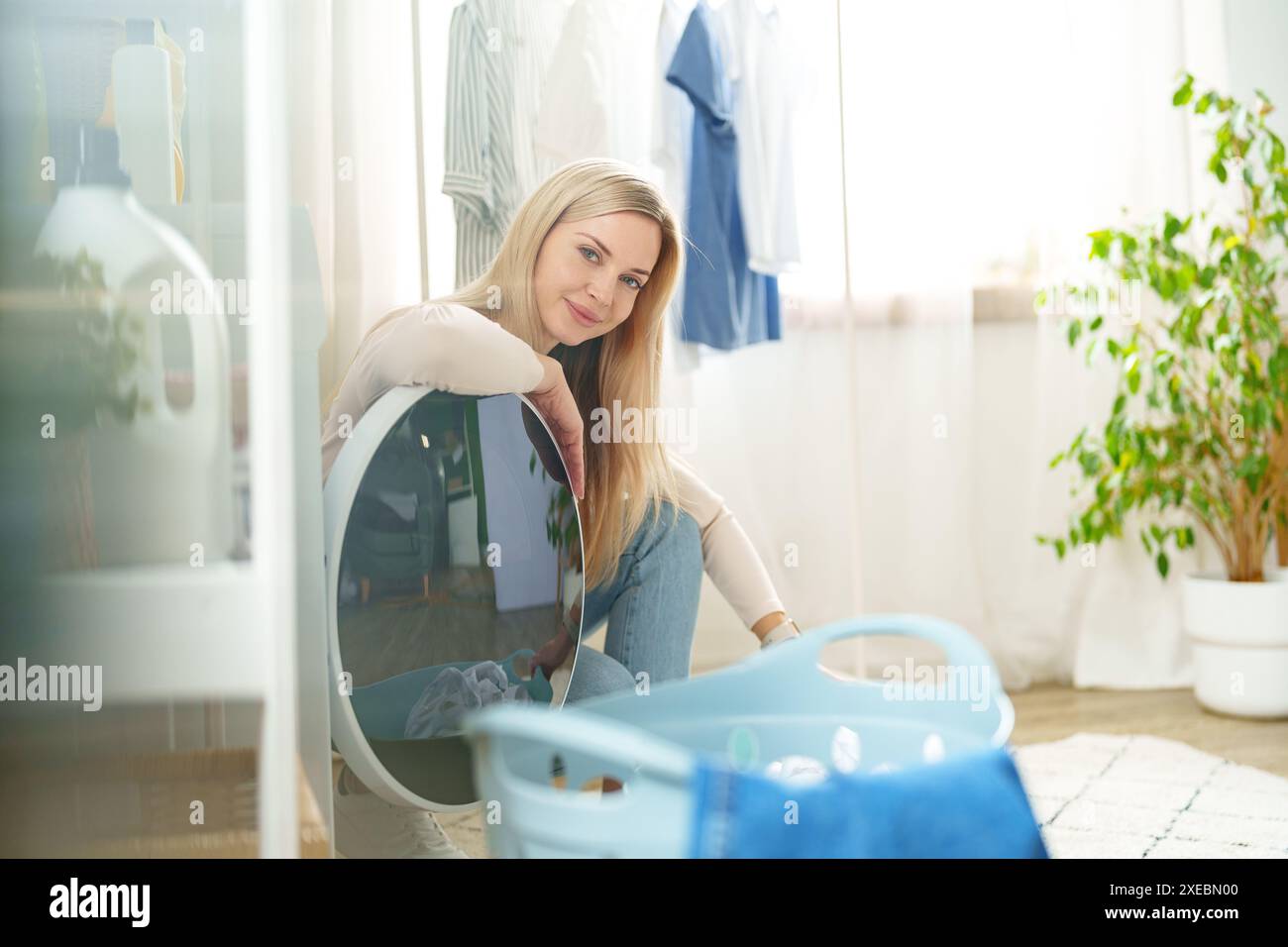 Woman Leaning On Washing Machine In Laundry Room Stock Photo - Alamy