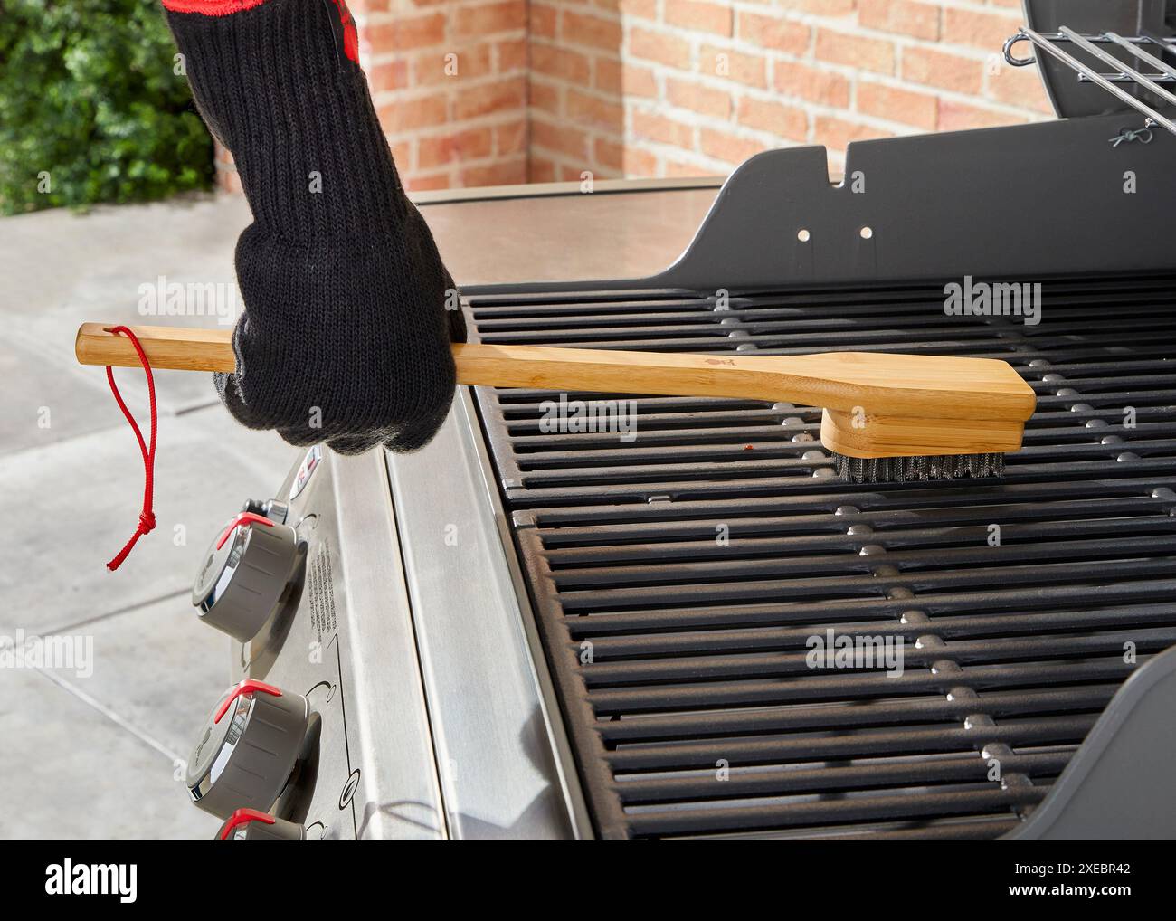 This is a handout photo of Man cleaning BBQ with a grill brush to ...