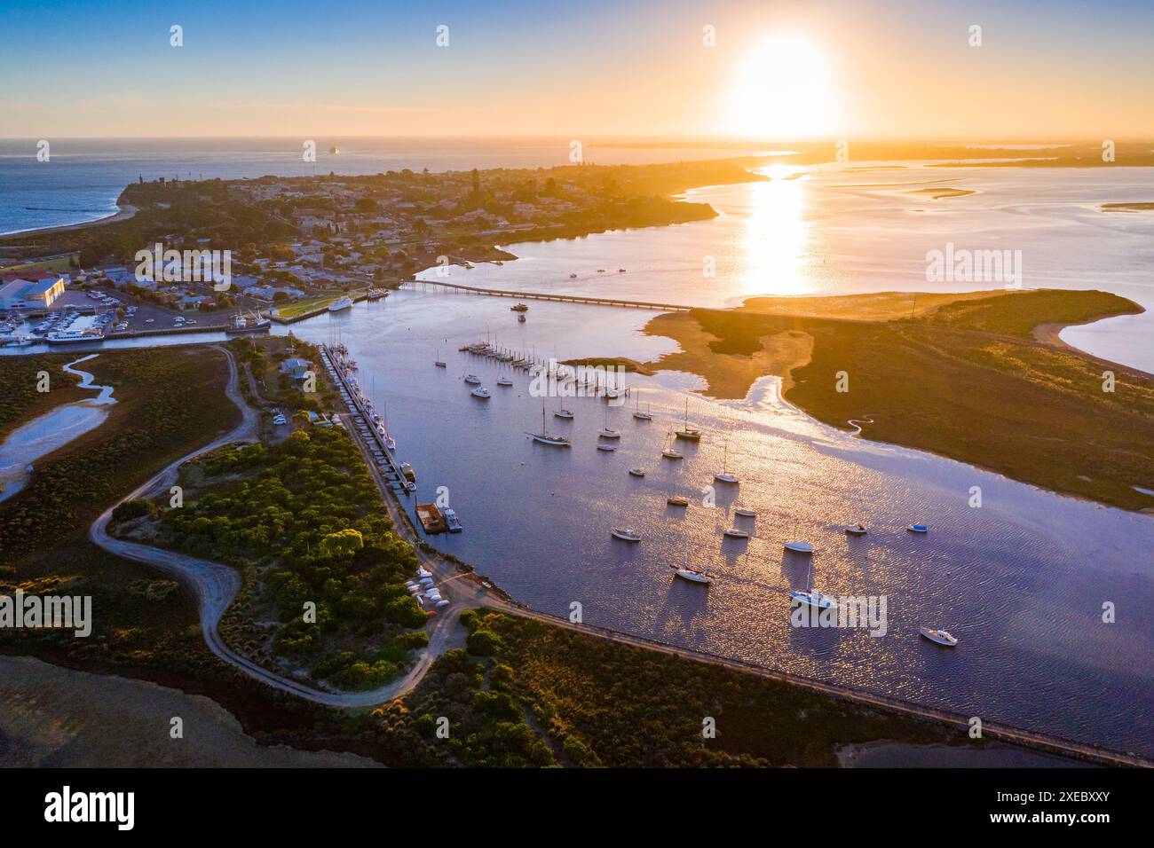 Aerial view a golden sunset over a coastal harbour between a township ...