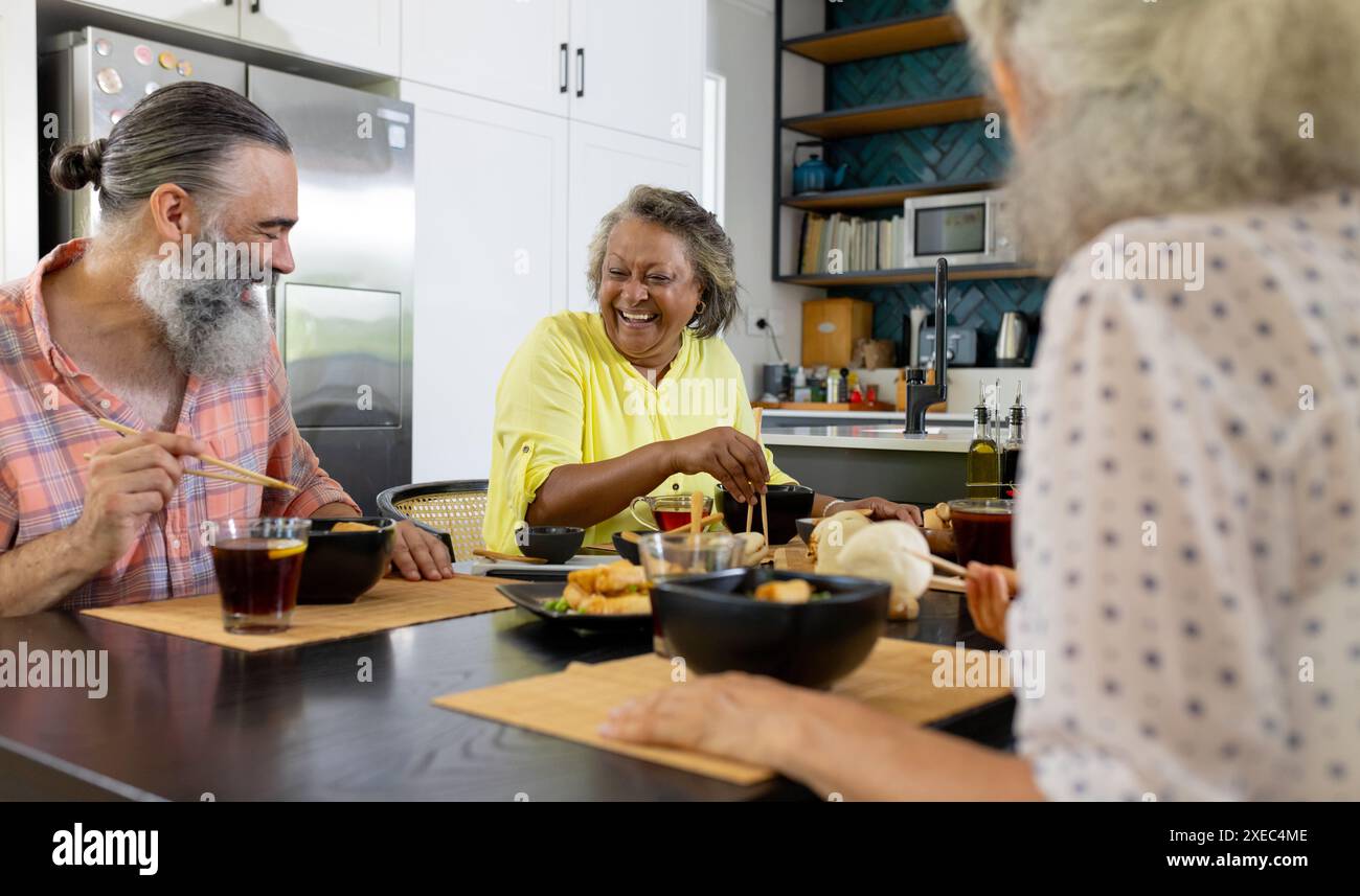 Enjoying meal together, group of senior friends laughing and dining at ...