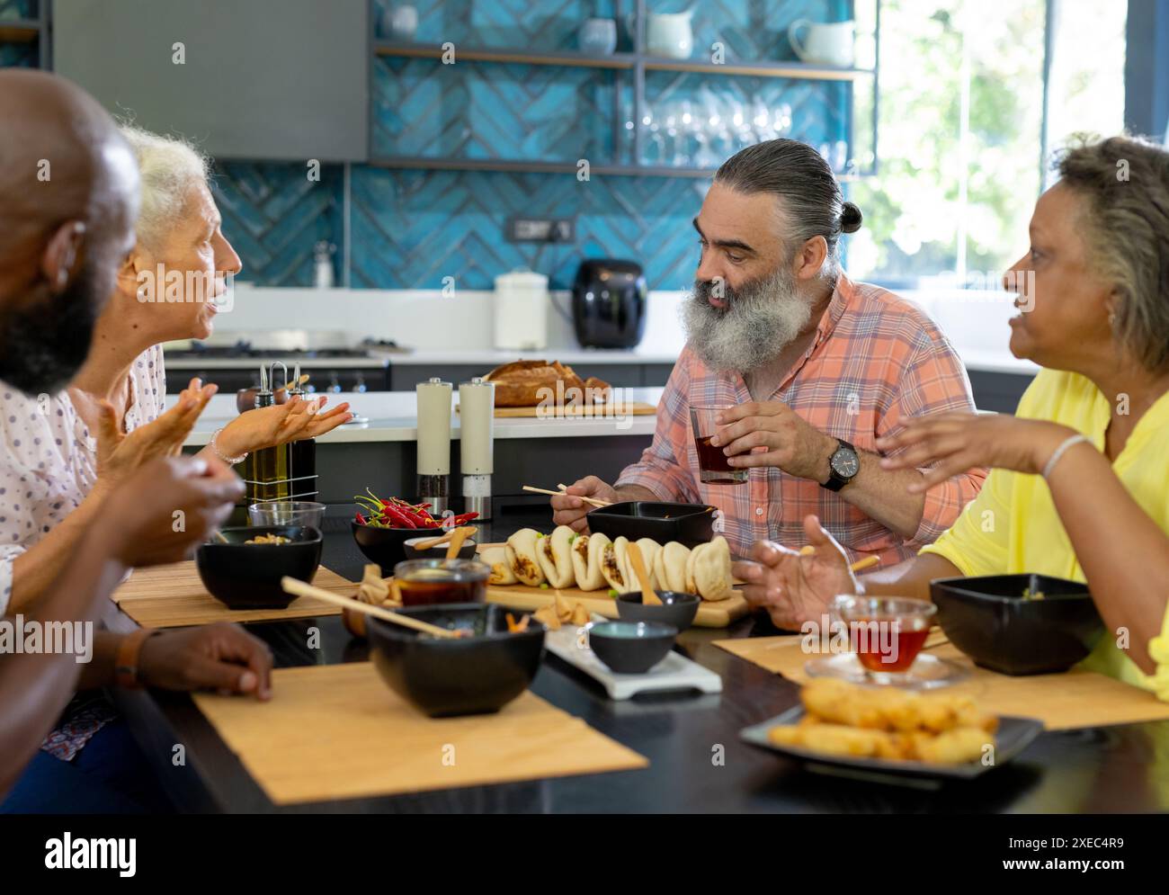 At home, Diverse group of senior friends enjoying meal and conversation ...