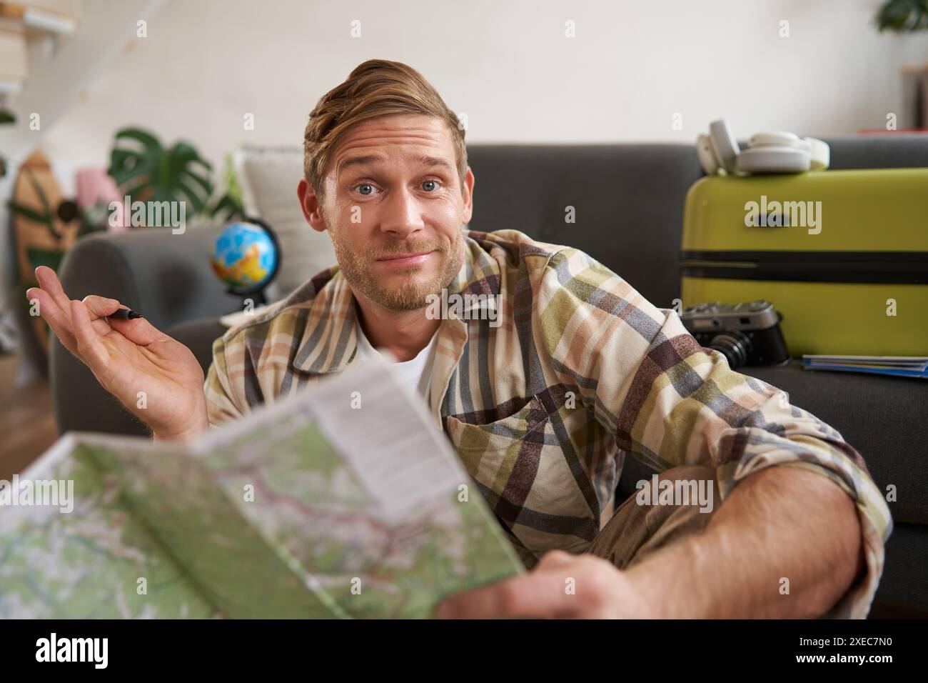 Image of shrugging man with road travel map, looks at camera with ...