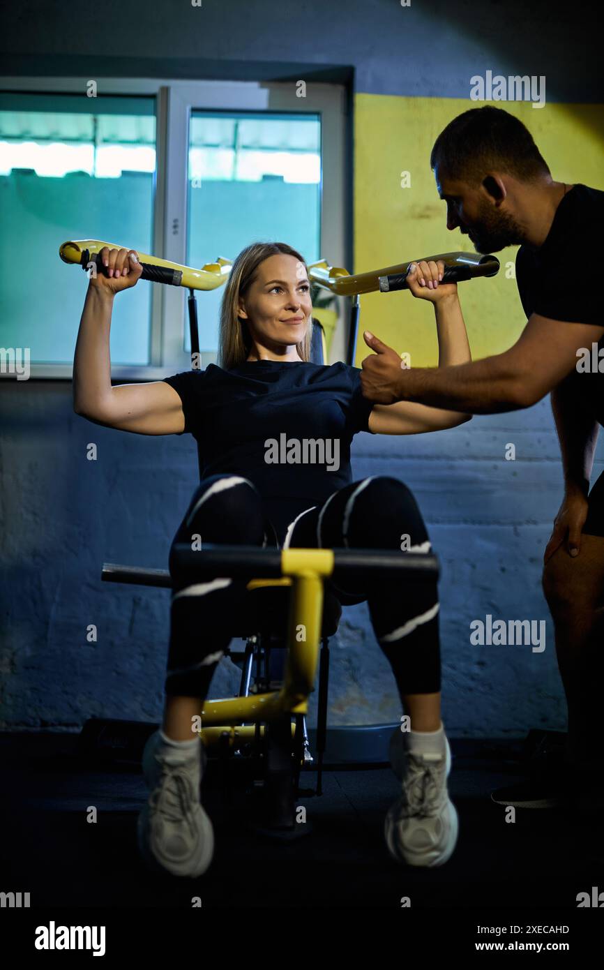 Personal coach assisting sportswoman in using machine during gym ...