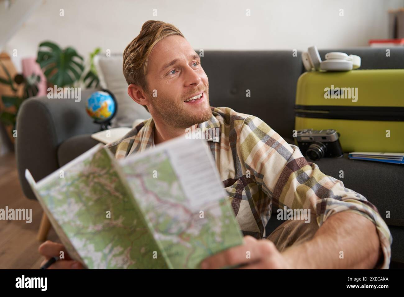 Handsome smiling tourist, man holds map, plans his holiday, going on ...