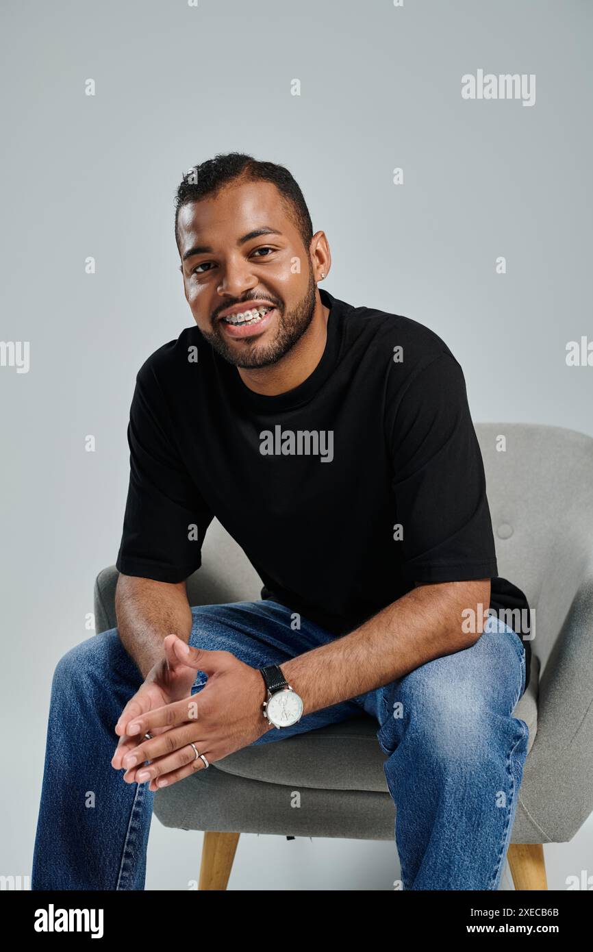 Stylish man sitting on chair, smiling brightly Stock Photo - Alamy