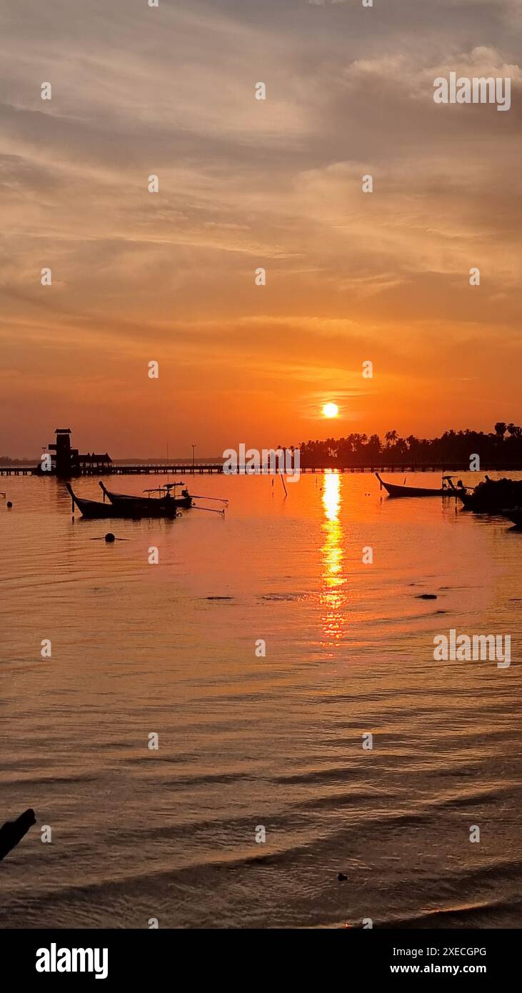 The sun sets over a tranquil body of water, casting a golden glow on ...