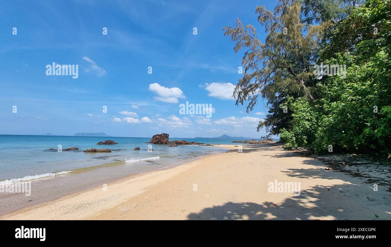 A sandy beach extends next to the sparkling ocean under a clear blue ...