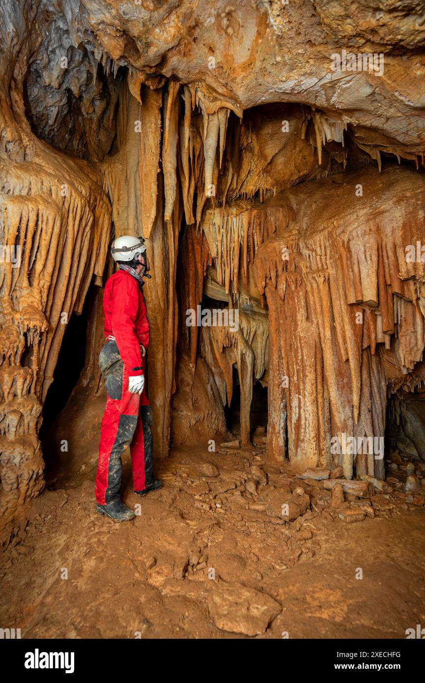 A speleologist with helmet and headlamp exploring a cave with rich ...