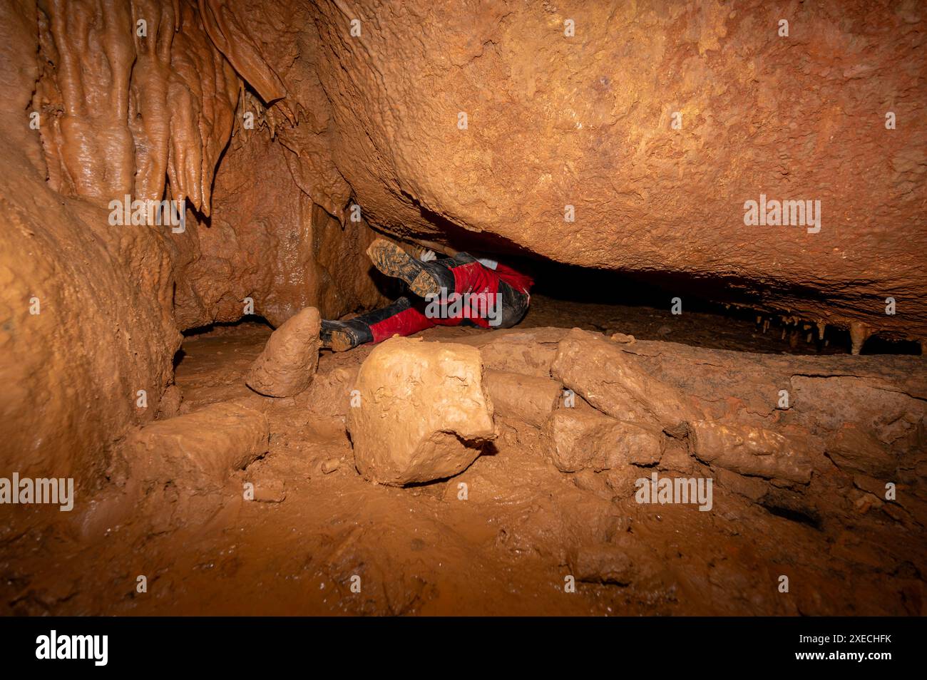 A speleologist with helmet and headlamp exploring a cave with rich ...