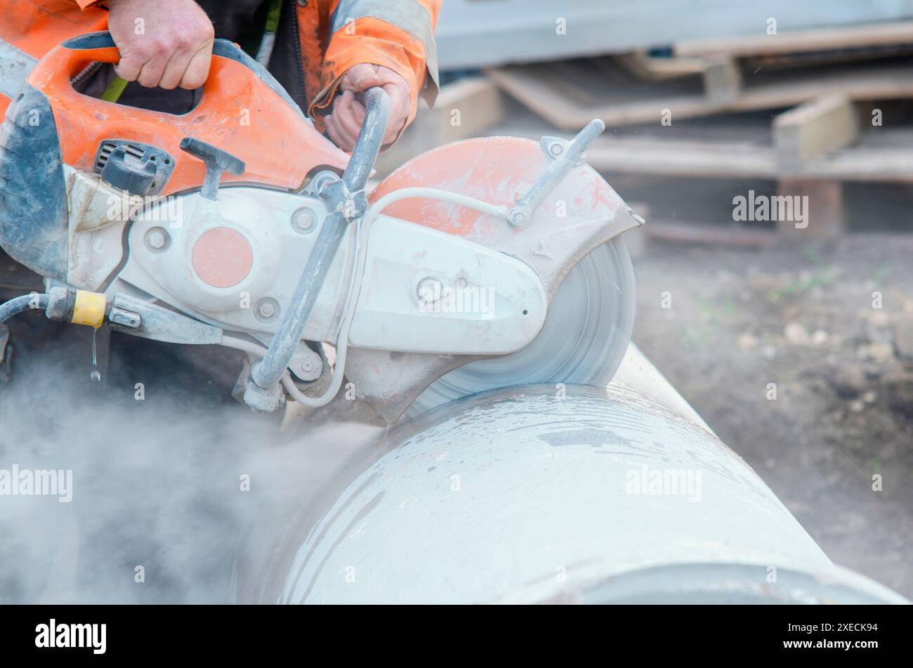 Construction worker cutting concrete pipe for drainage using a cut-off saw. Cutting concrete ...