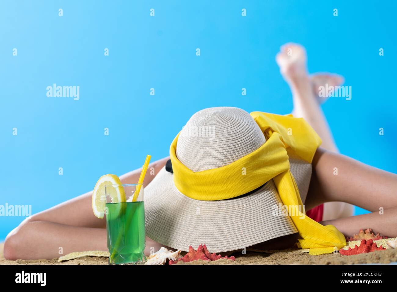 A young teenager is lying on the beach with an alcoholic drink and ...