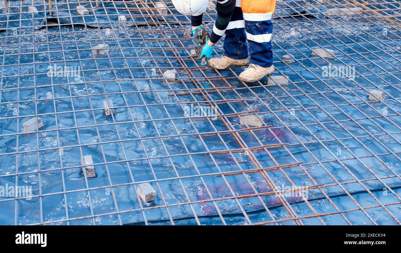 Construction worker fixing steel rebar with pincers and wire at a ...