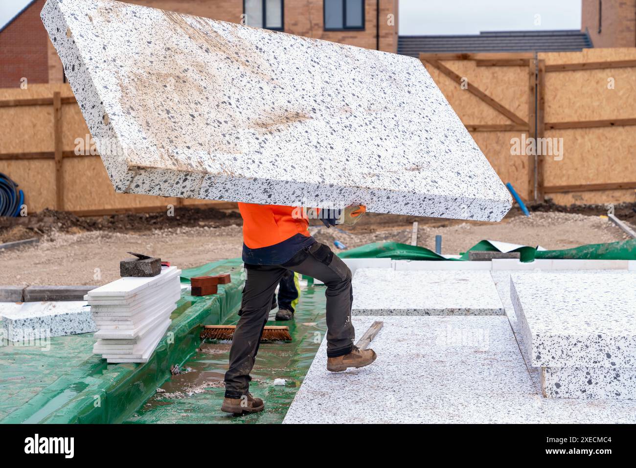 Builder placing polystyrene insulation boards on waterproofing membrane ...