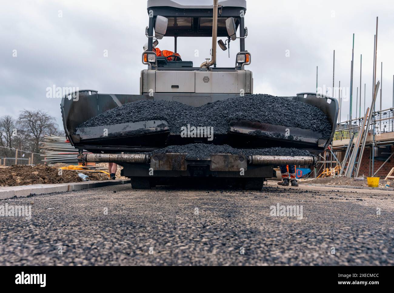 Asphalt paver filled with hot tarmac laying new road surface on new ...