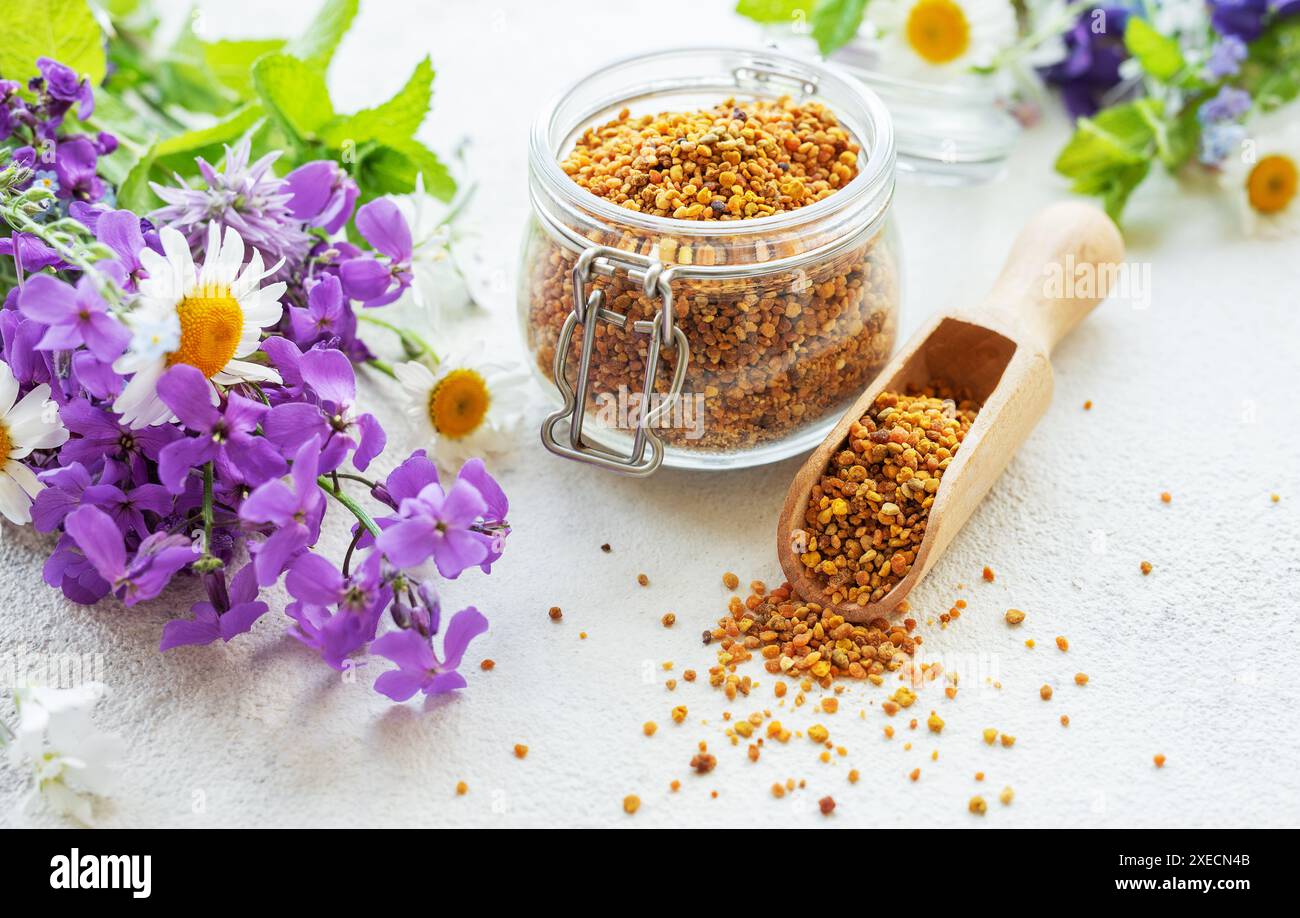 Healthy bee pollen grains. Bee pollen on a glass jar and wild flowers ...