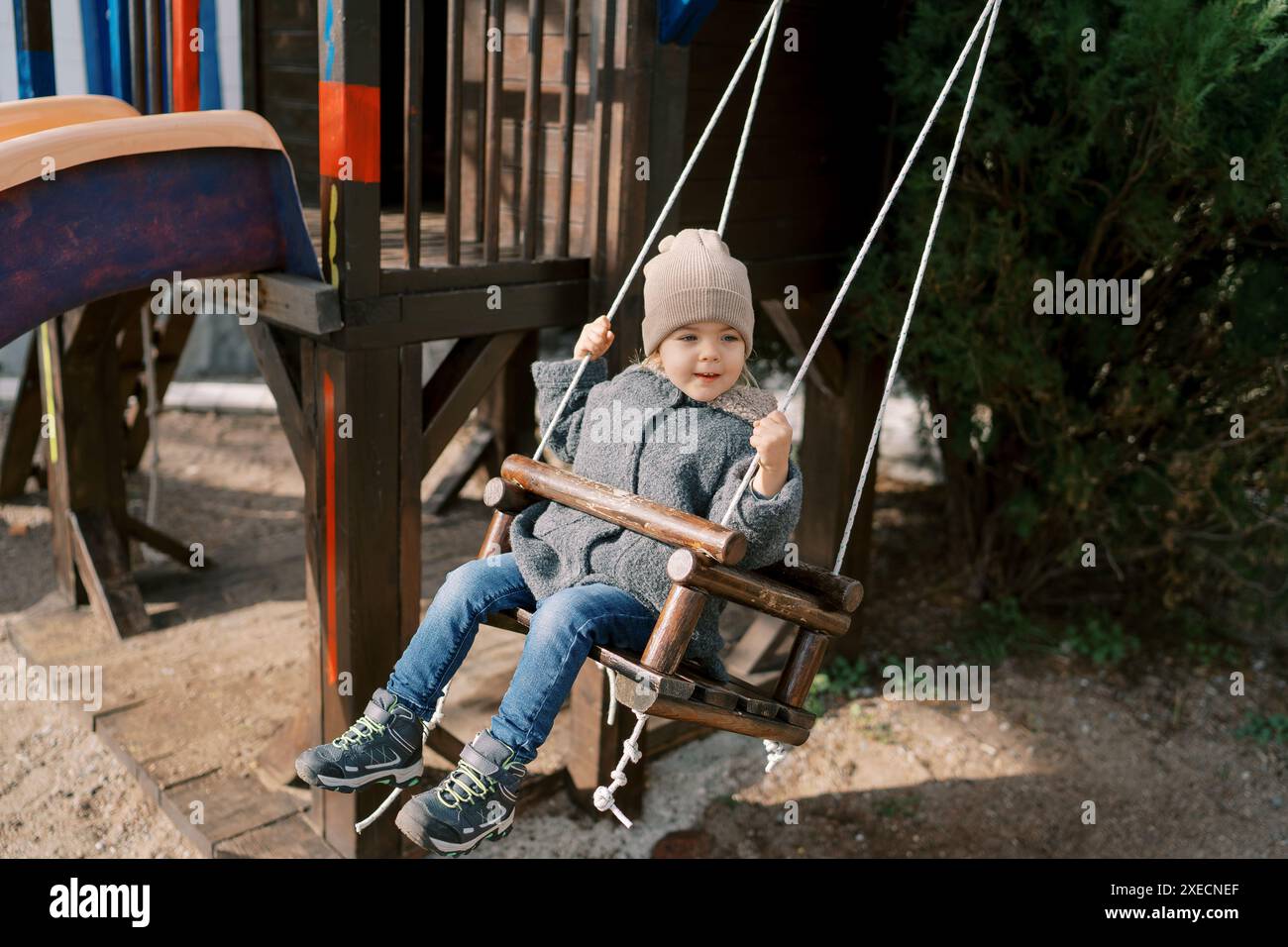 Little girl swings on a rope swing at the playground and looks away Stock Photo - Alamy