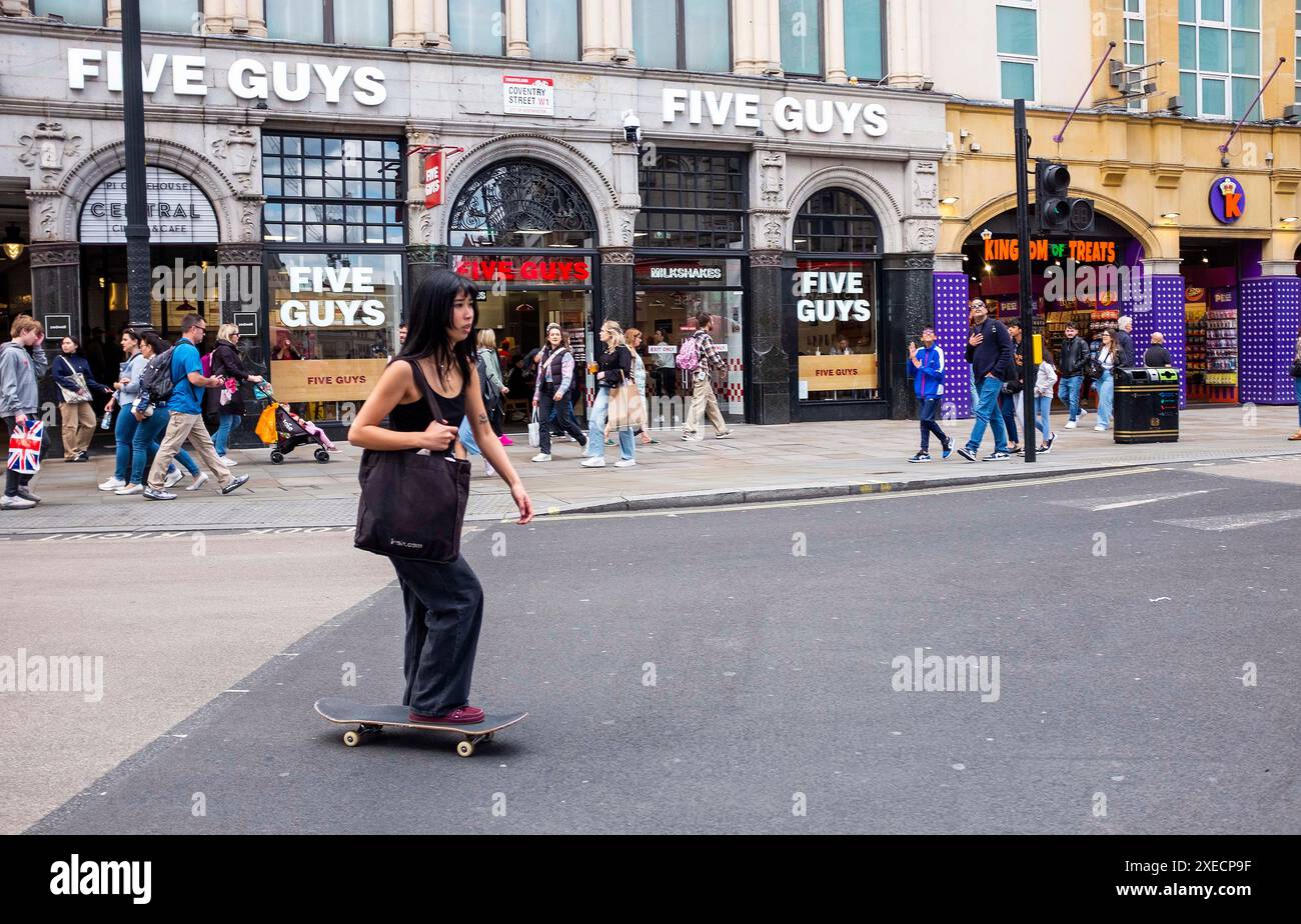 A young woman skateboarding along Coventry Street in London , England ...