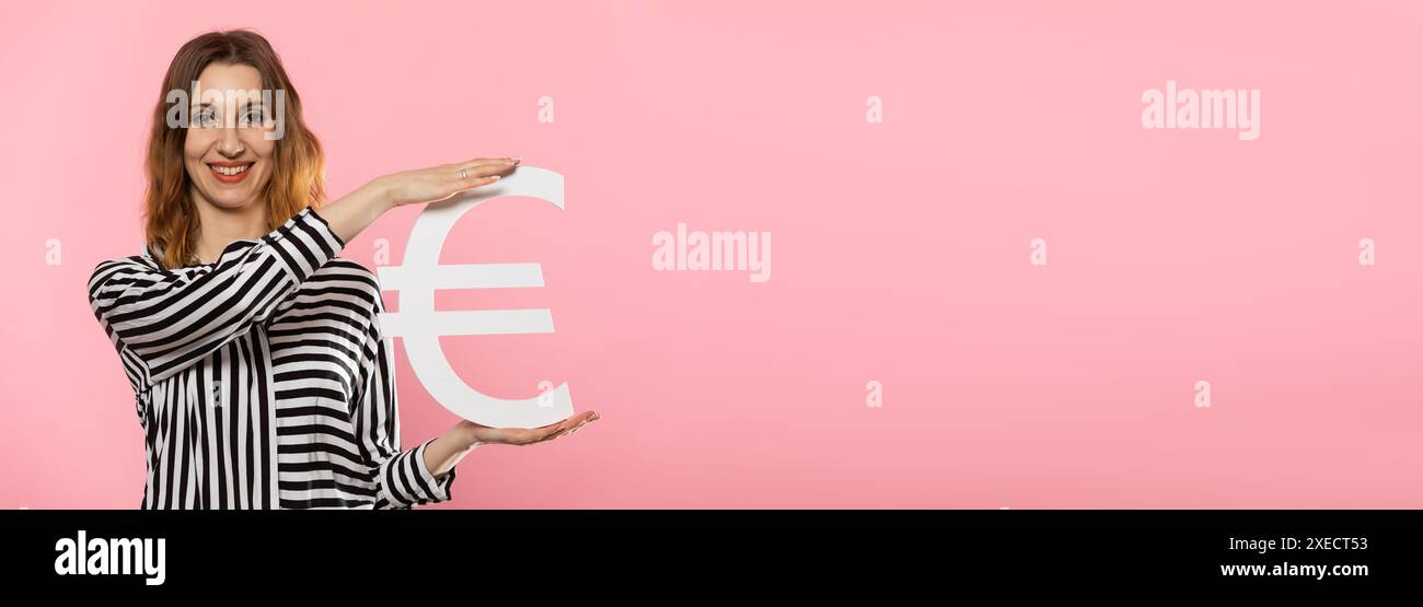 The girl holds a large euro symbol in her hands. Shape of the currency ...