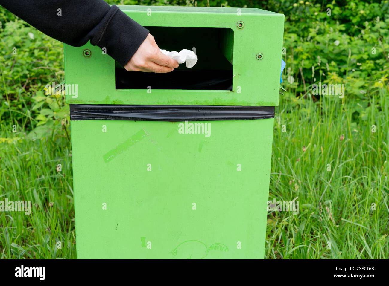 Arm throwing waste into trash can in an outdoor recreation resort ...
