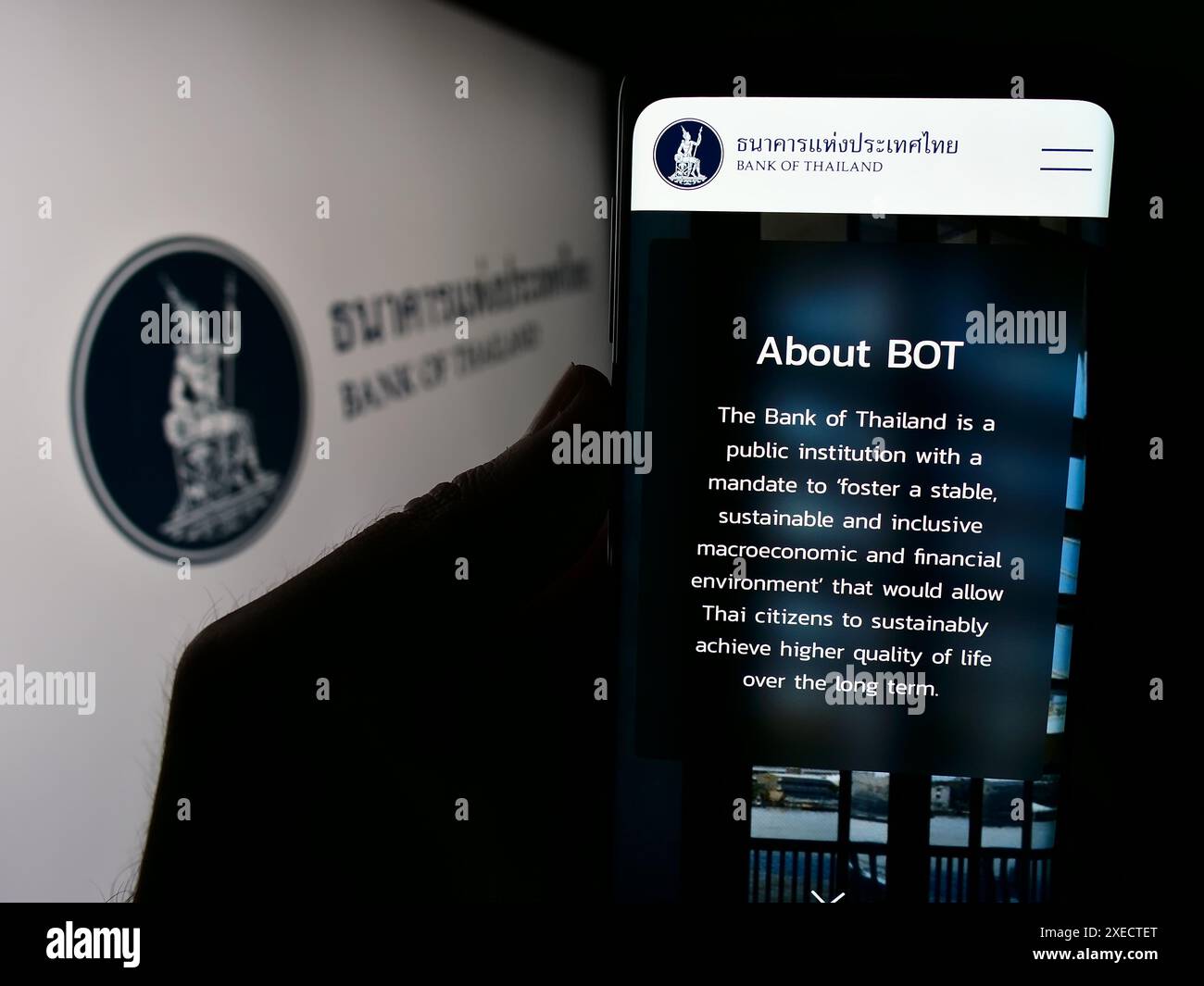 Person holding cellphone with webpage of Thai financial institution ...