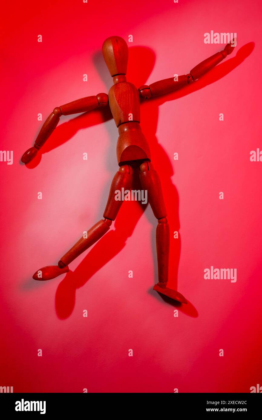 A small wooden artists model or mannequin laying down as if dead on a ...