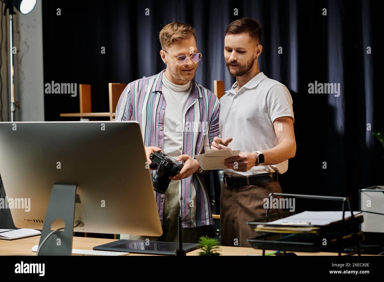 Two men in comfortable attire are focused on a computer screen together Stock Photo - Alamy