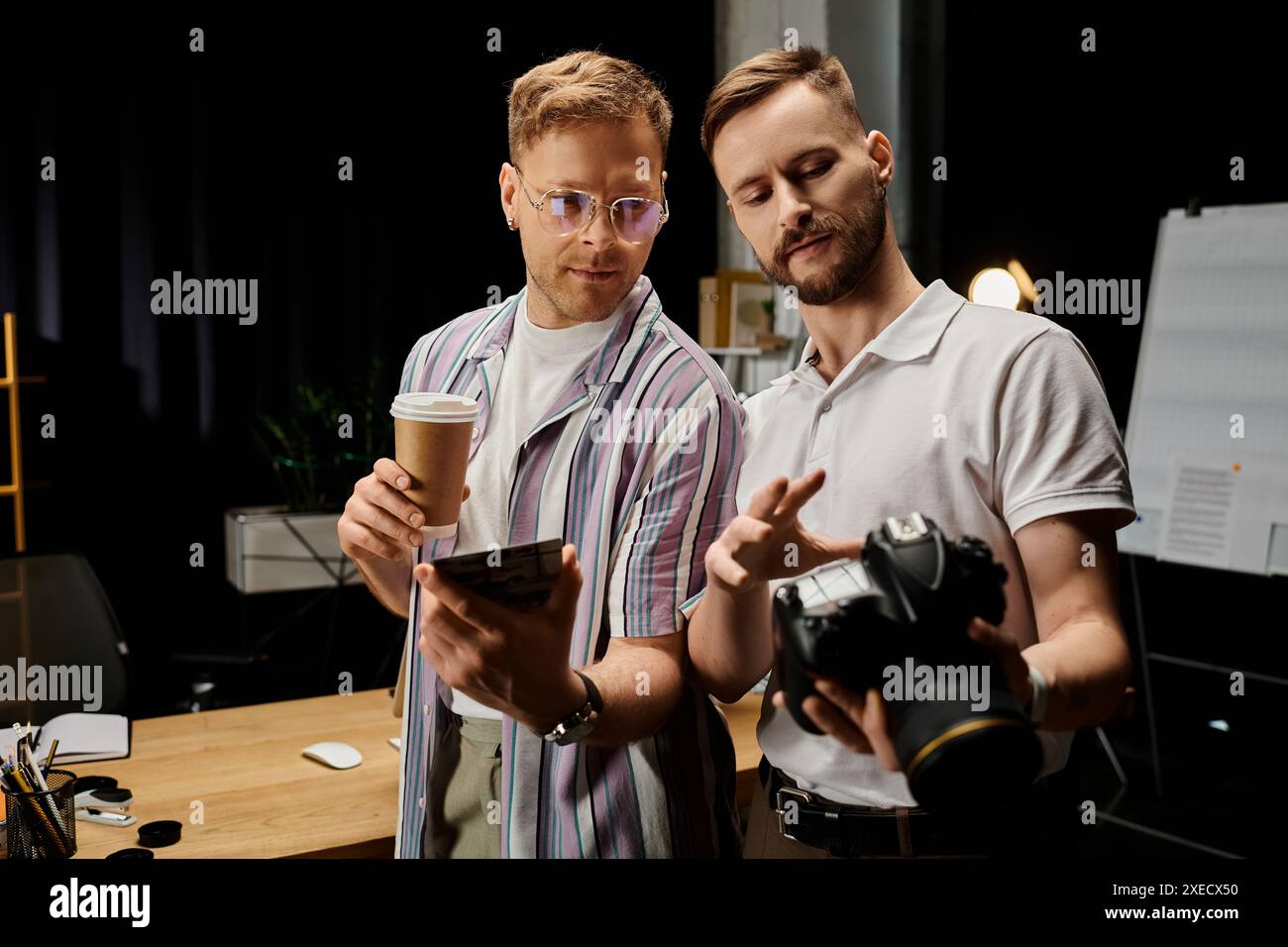Two men, dressed casually, stand together in an office setting Stock ...