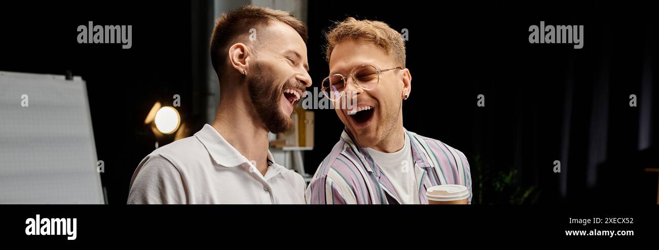 Two cheerful men collaboratively standing together in a workplace ...