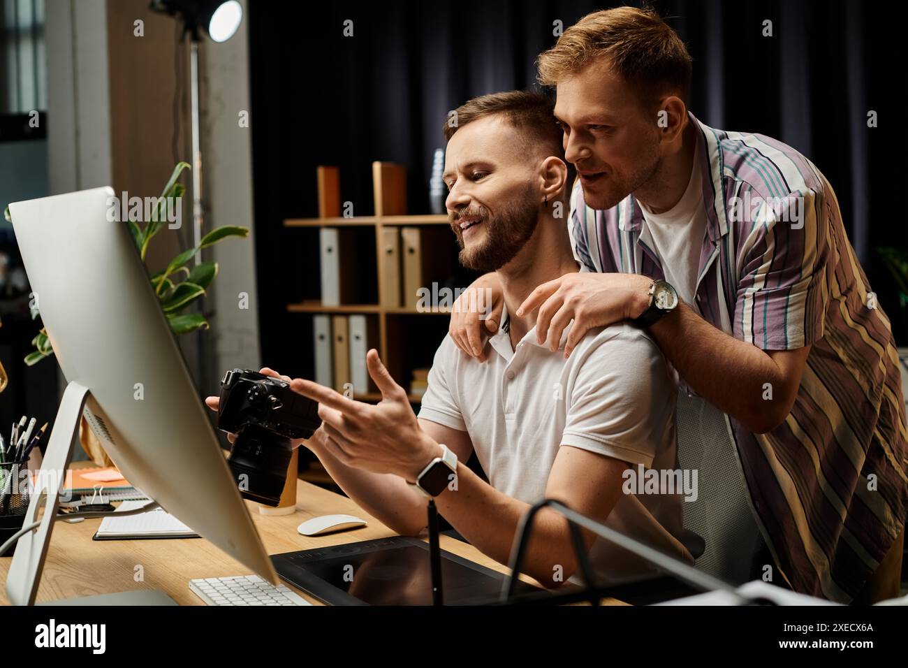 Two men engage with a computer screen in a modern office setting Stock ...