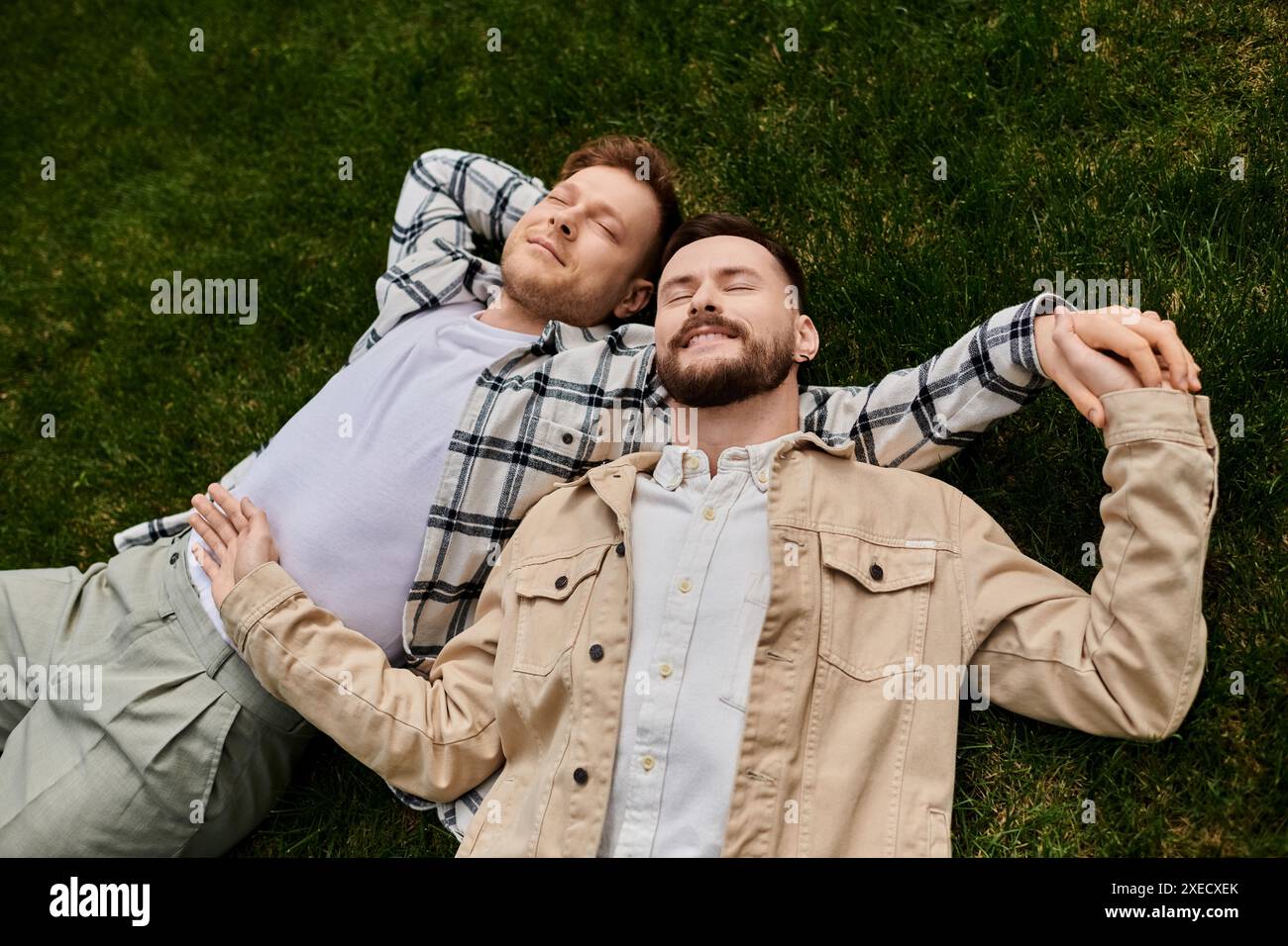 Two men relax comfortably on a vibrant green field Stock Photo - Alamy