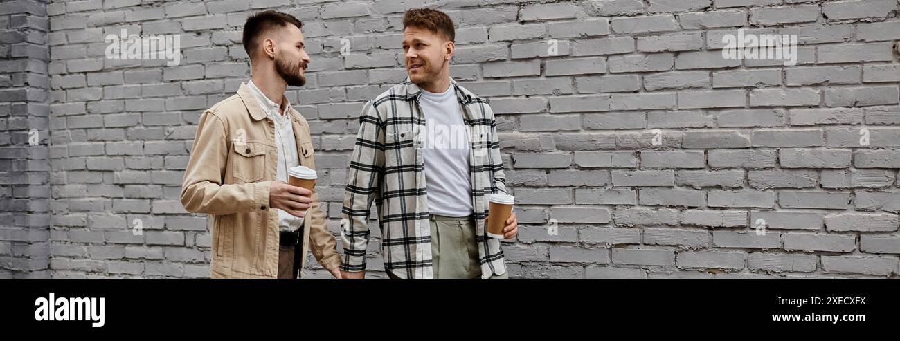 Two men in casual attire standing by brick wall Stock Photo - Alamy
