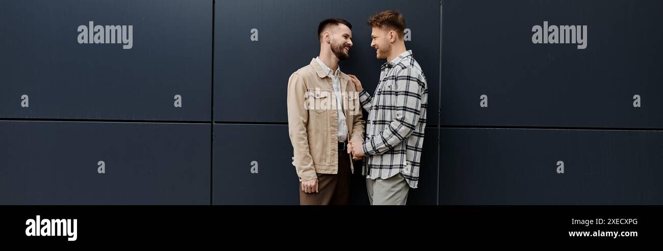 Two men in casual attire standing proudly by a wall Stock Photo - Alamy