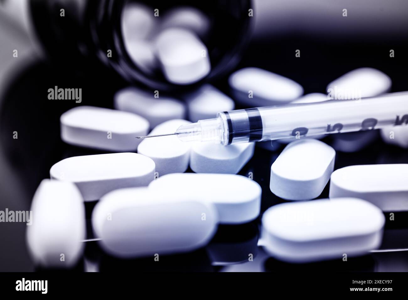 A close-up view of white pharmaceutical pills and a syringe on a ...