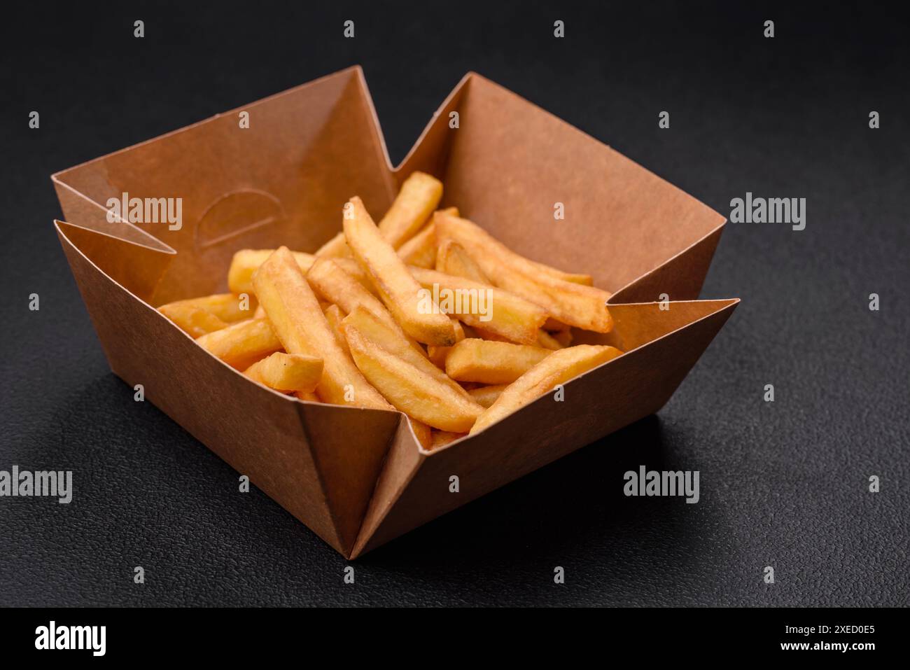 Delicious crispy french fries with salt and spices in a cardboard box ...